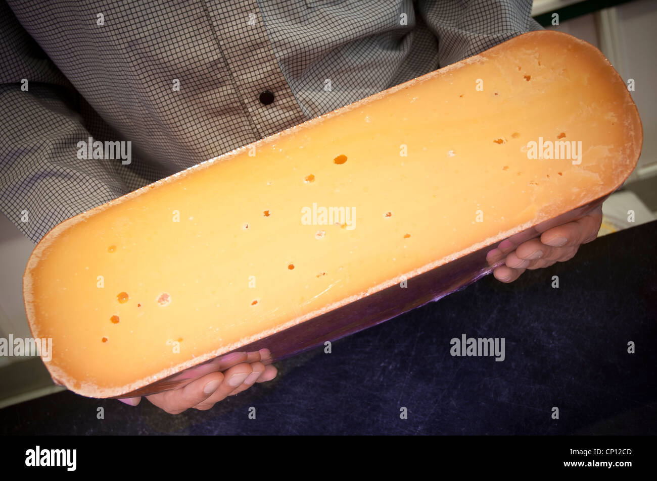 Man in store holding a big Gouda Cheese cut in half Stock Photo - Alamy