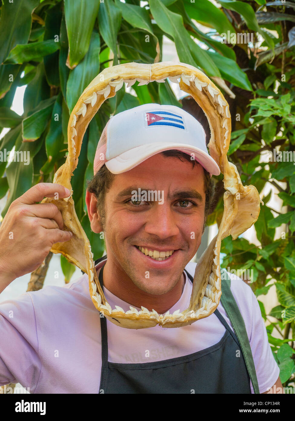 A 20-30 year old Cuban male holds a shark's jaw, with teeth, in front ...