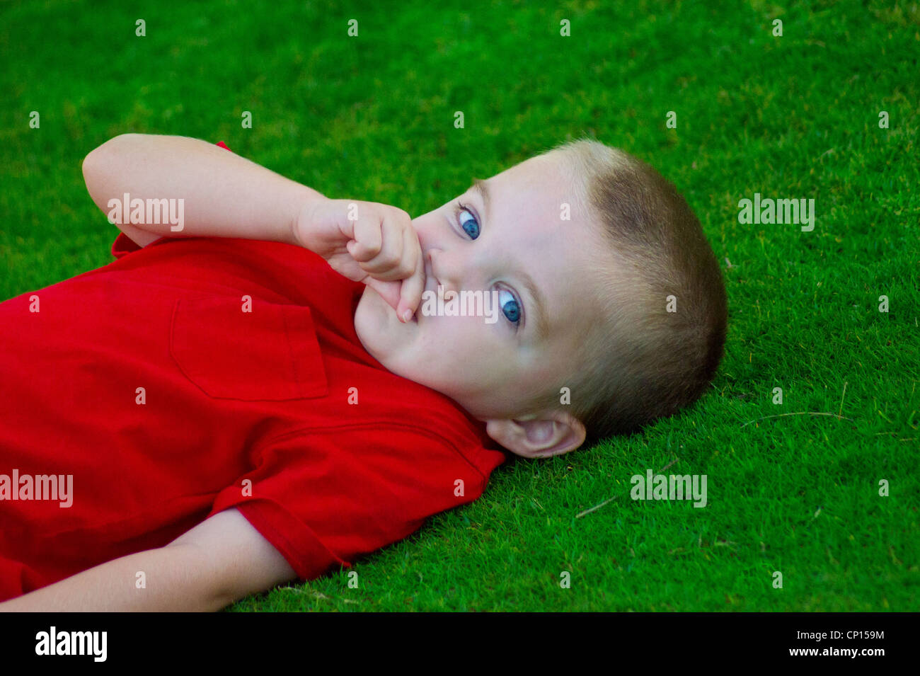 Four year old autistic boy lays on grass, primary colors Stock Photo ...