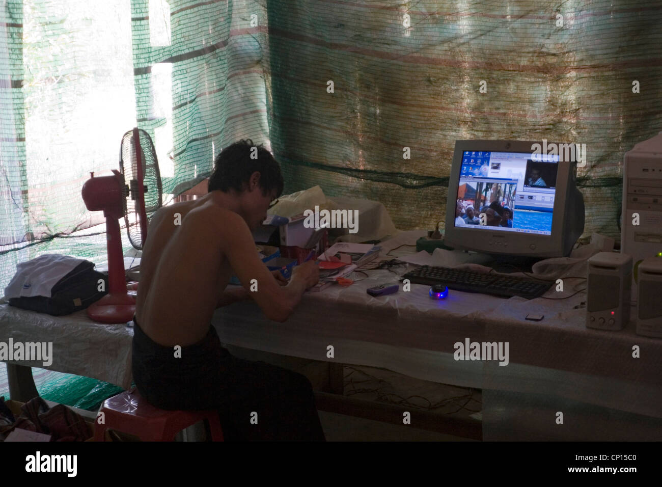 A young Asian man is using a computer inside his wooden shack in Pang ...