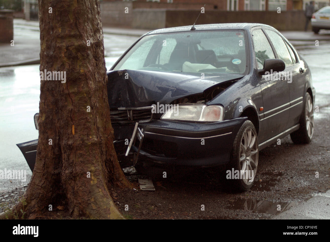 Road traffic accident in the rain. Car hits tree on busy main road in ...