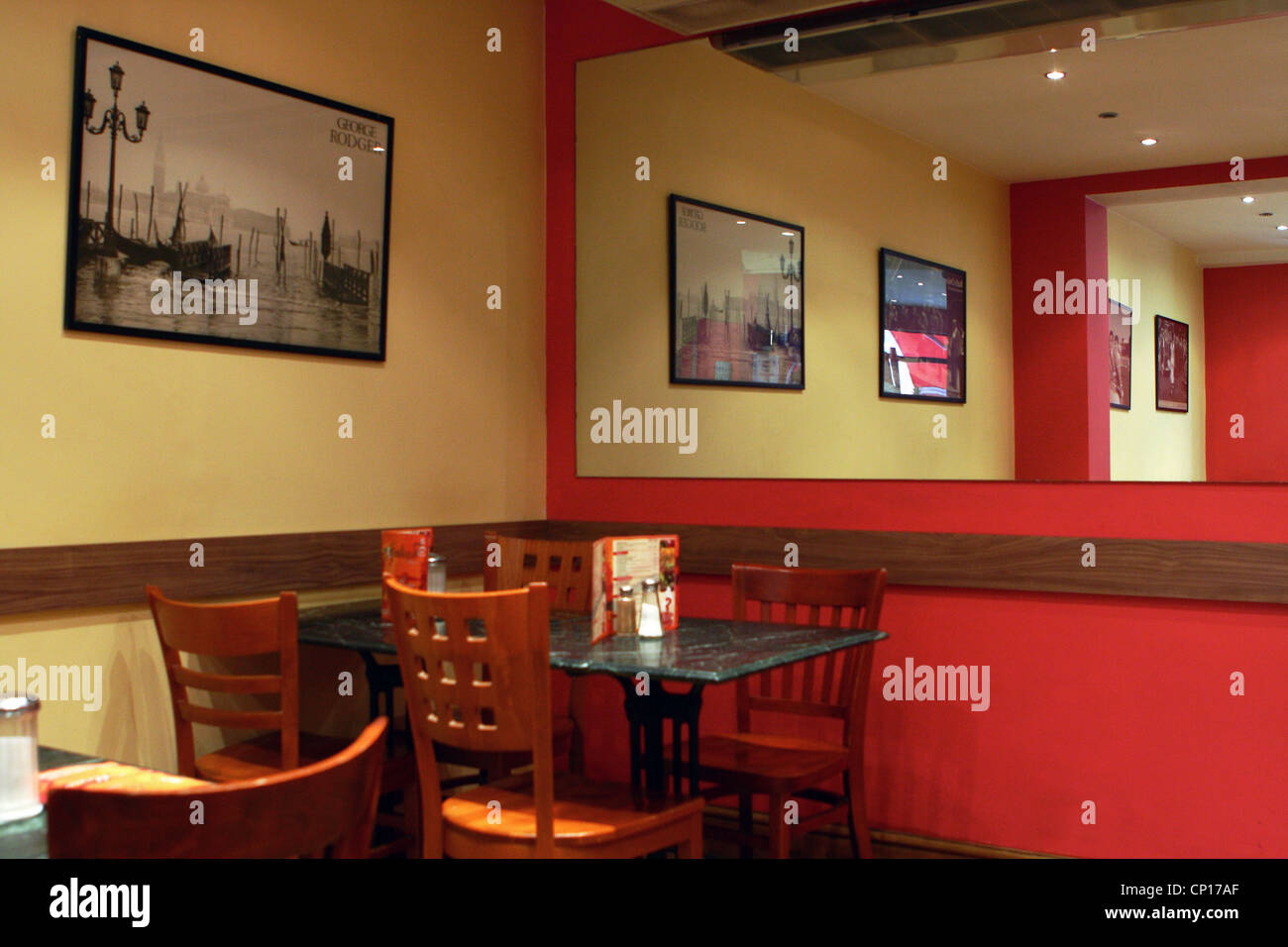 Part of the inside of a cafe with reflections in a large mirror fixed ...