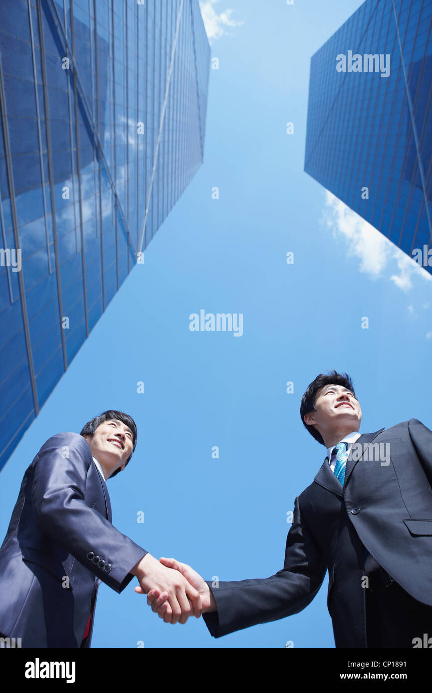 Businessmen shaking hands around the buildings Stock Photo - Alamy