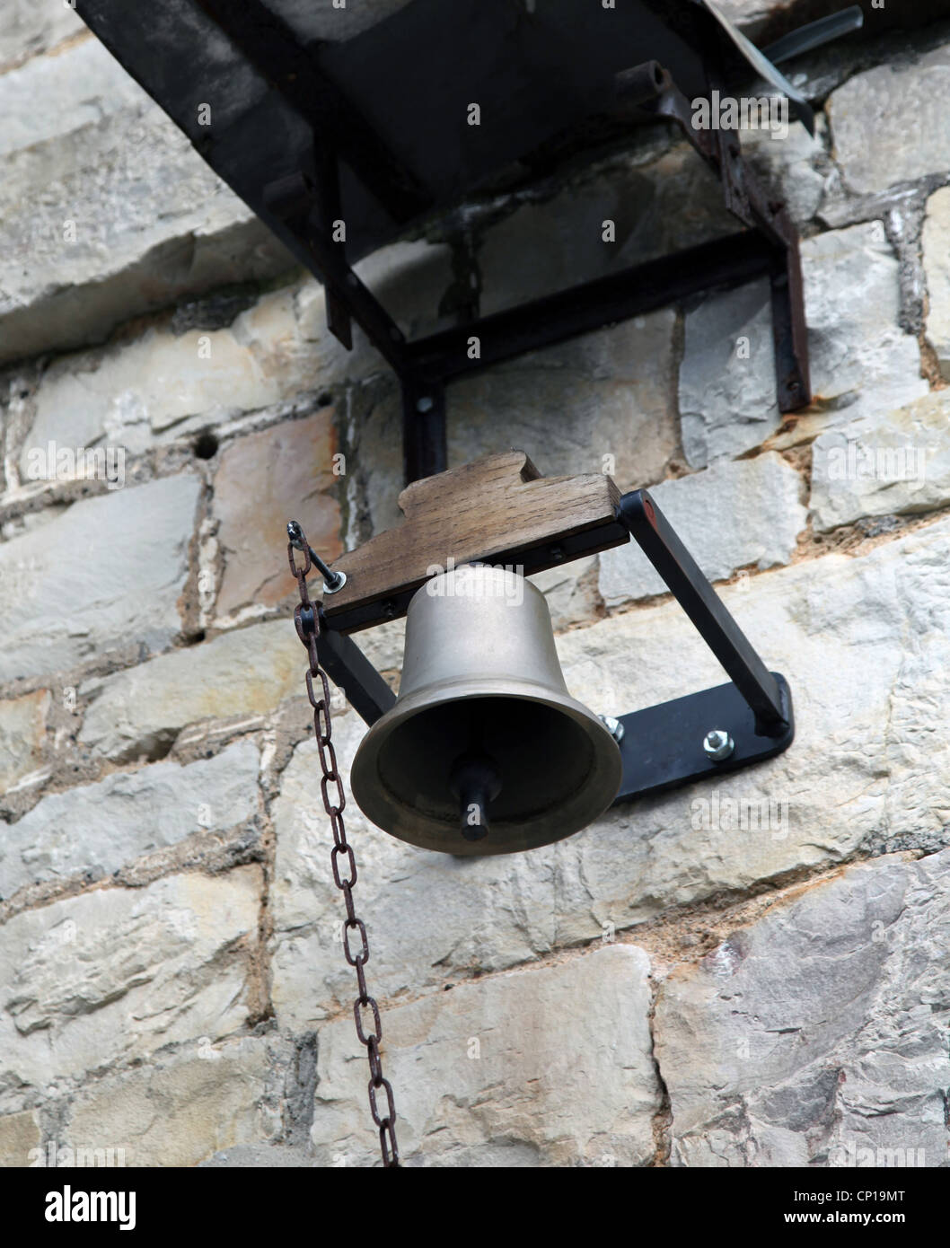 it's a photo of a big bell hanged against the wall in a school or stone ...