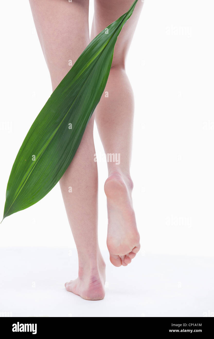 The legs of woman with green leaf Stock Photo - Alamy
