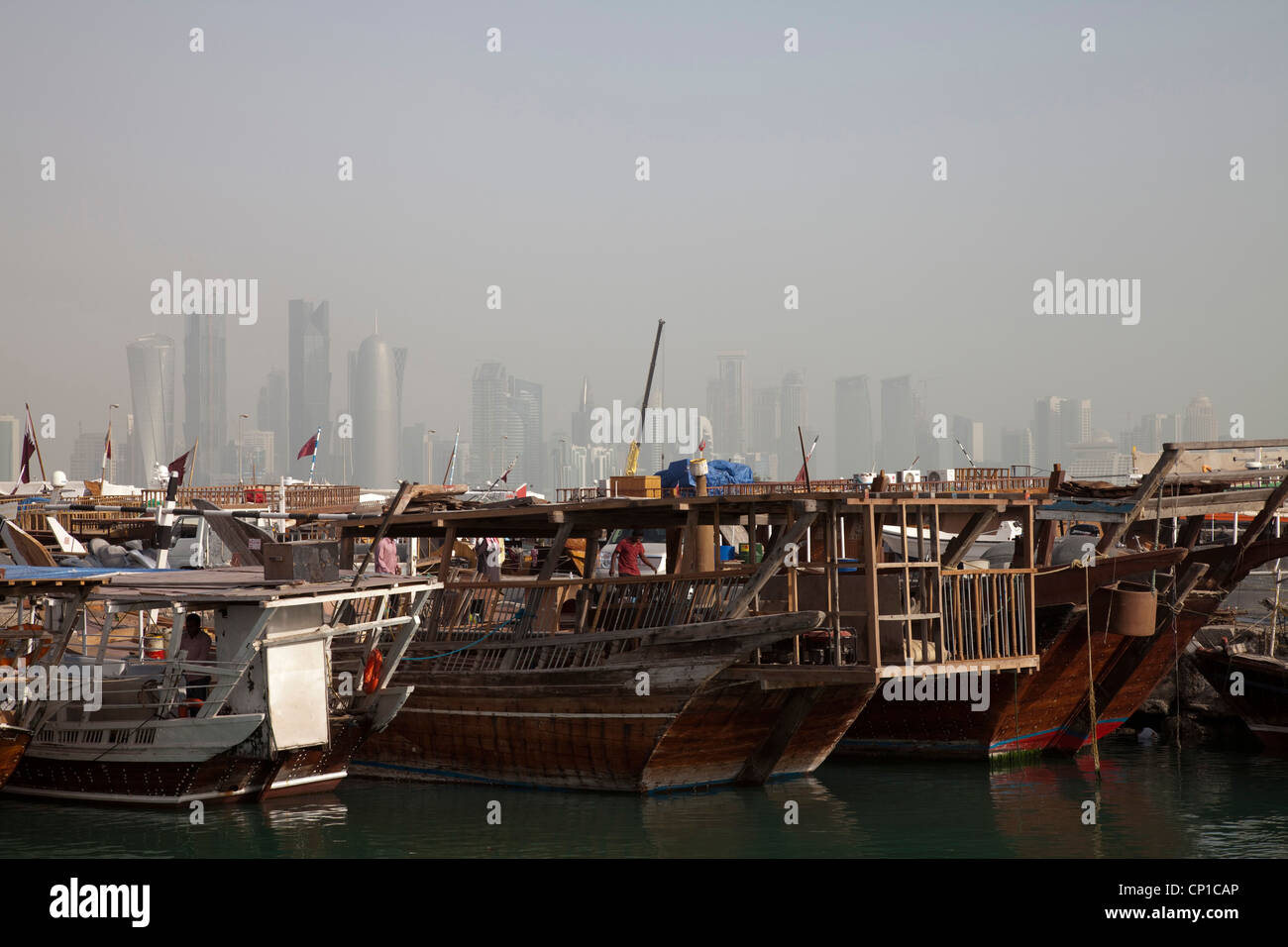 Traditional boats in Doha harbour with a dusty skyline behind Stock ...