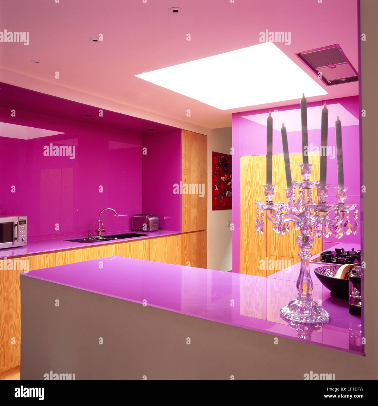 A modern pink kitchen with wooden units and purple work tops with a ...