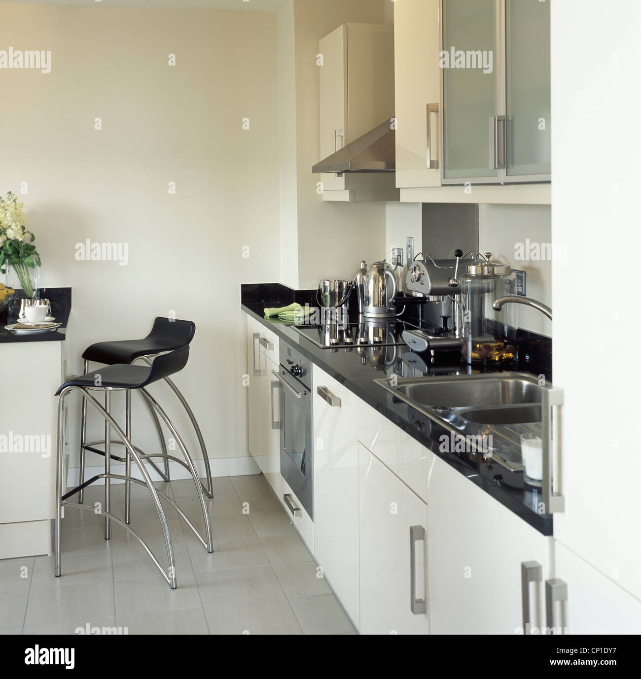 Kitchen with white cupboard units and breakfast bar with stools Stock ...