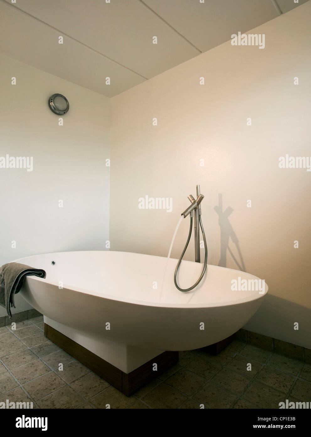 Water running into modern freestanding bathtub in minimalist bathroom ...