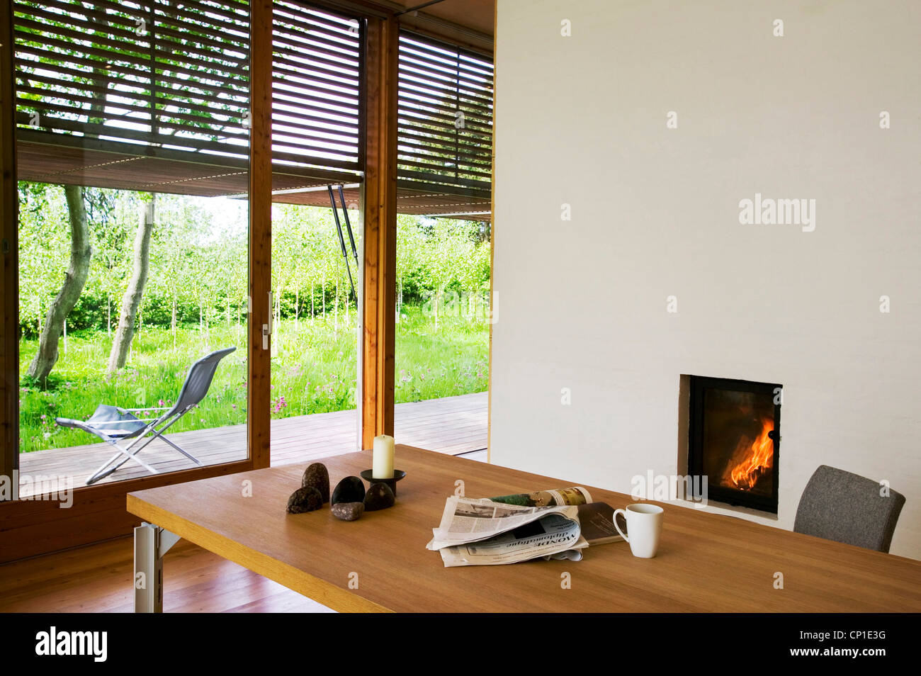 Wooden table in front of lit fire in simple fireplace in modern room ...