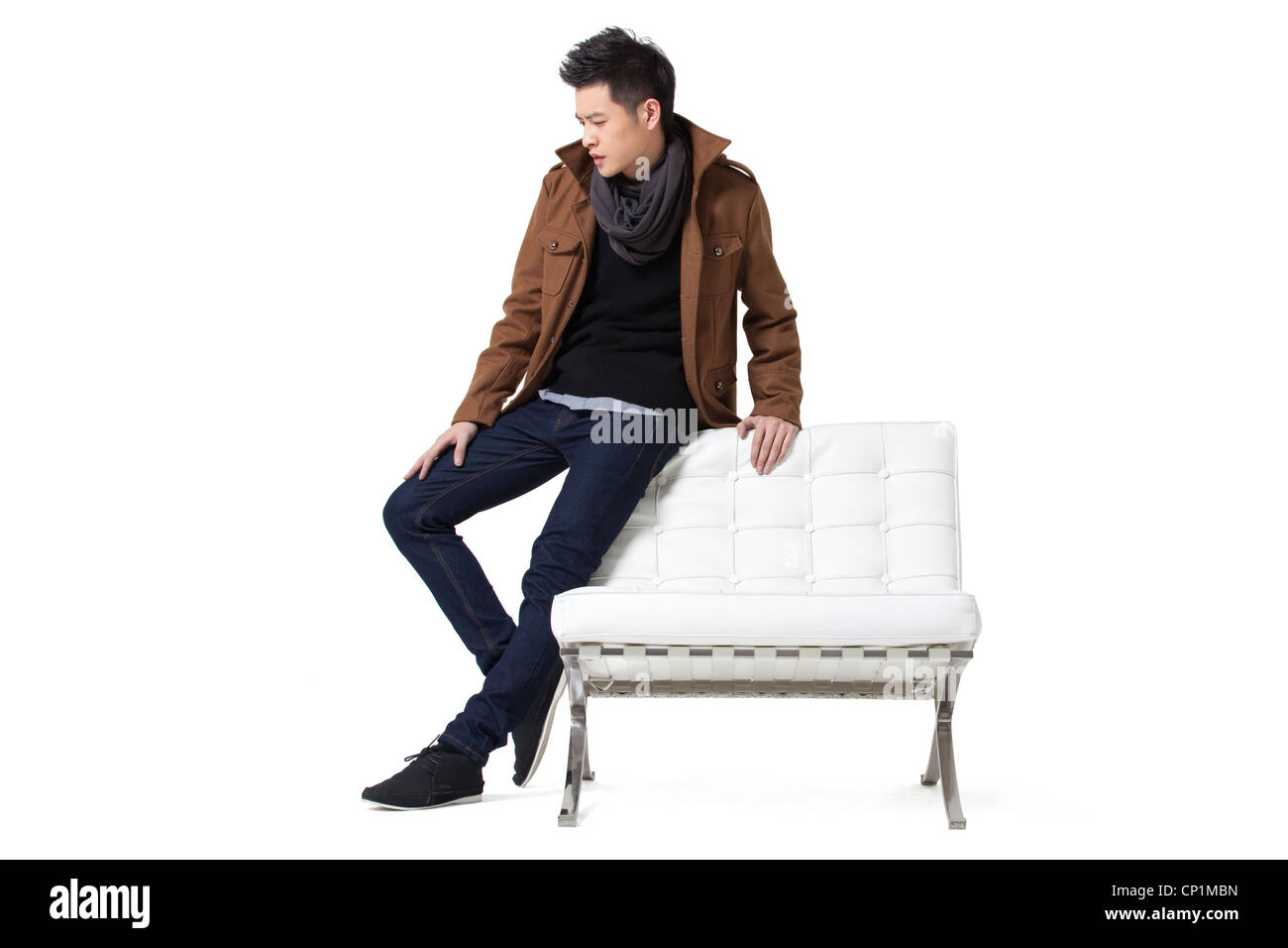 Stylish young man standing by chair Stock Photo - Alamy