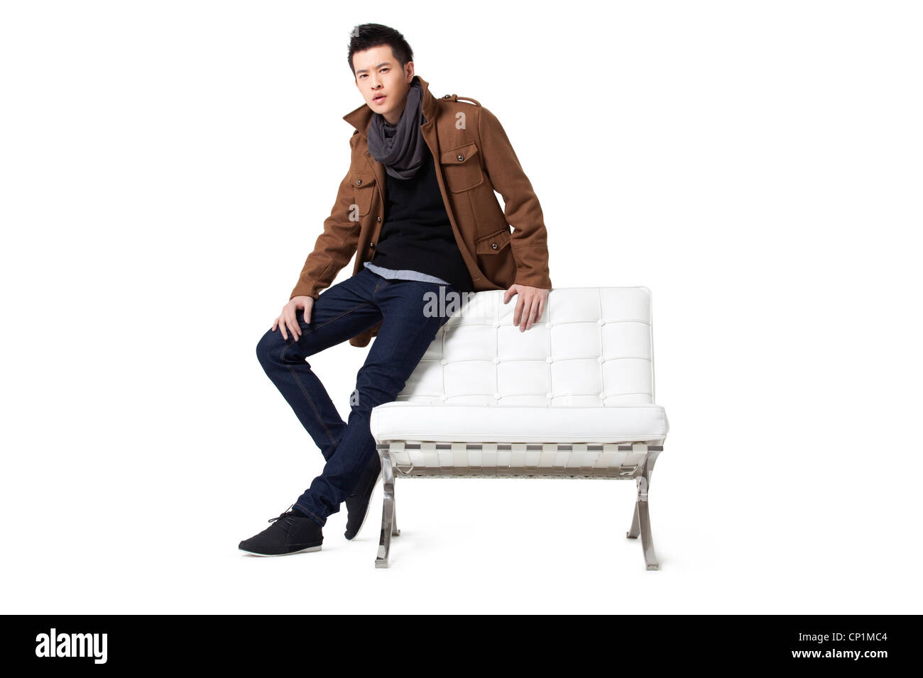 Stylish young man standing by chair Stock Photo - Alamy