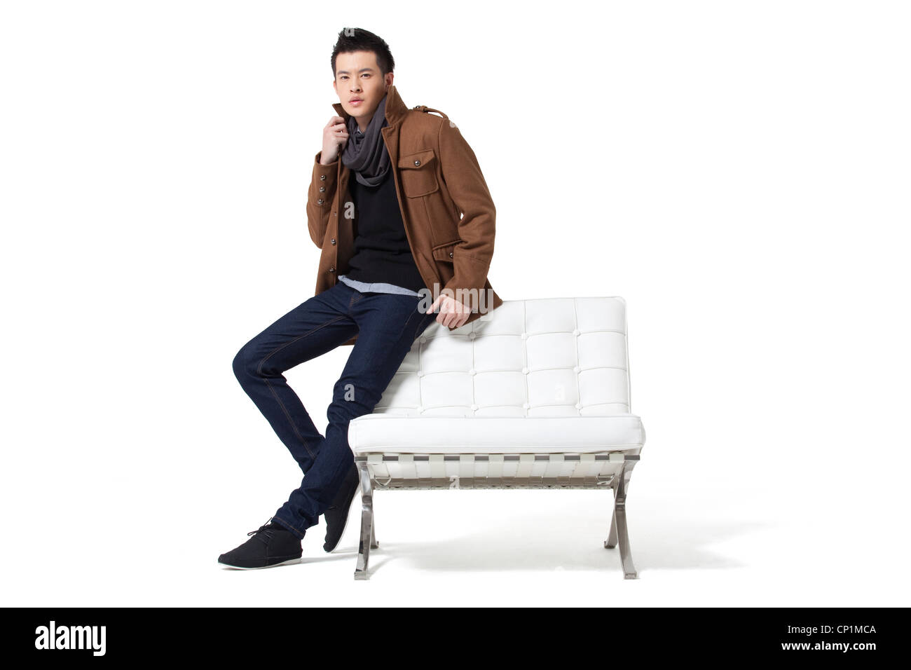 Stylish young man standing by chair Stock Photo - Alamy