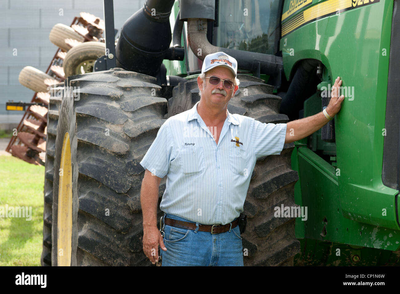 Farmer standing in front of tractor and grain operation on farm Stock ...
