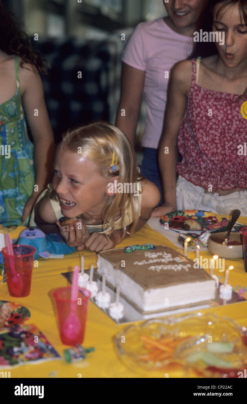 Girl blowing candles out on cake at birthday party Stock Photo - Alamy