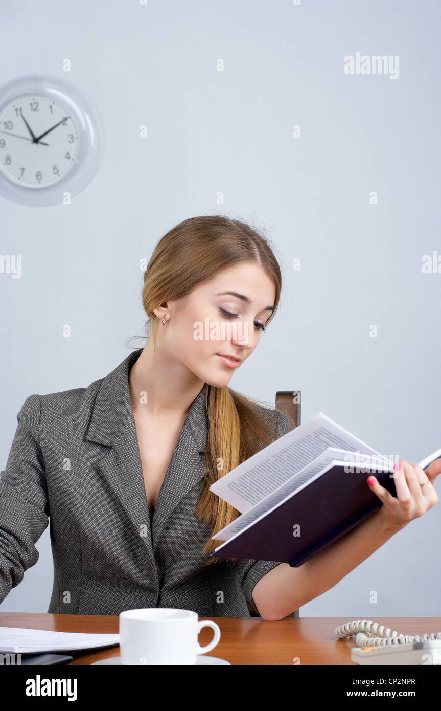 Beautiful business woman at desk, reading book Stock Photo - Alamy