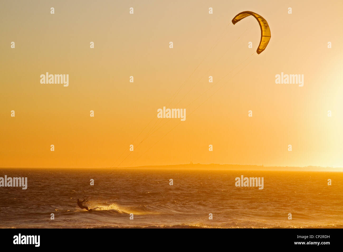 Kite surfer at sunset with Robben Island just visible on the horizon ...