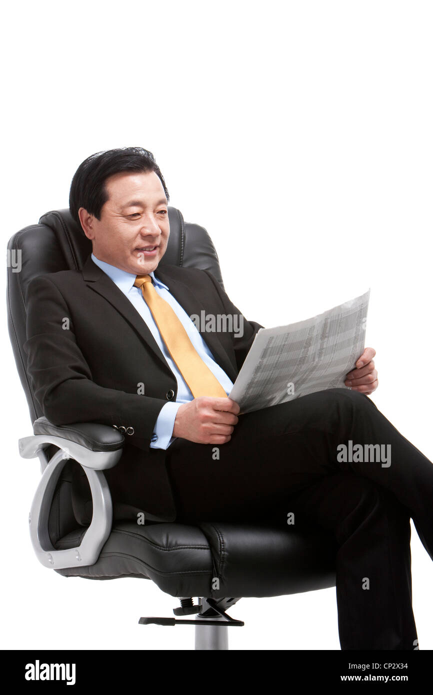 Senior businessman reading newspaper on director's chair Stock Photo ...