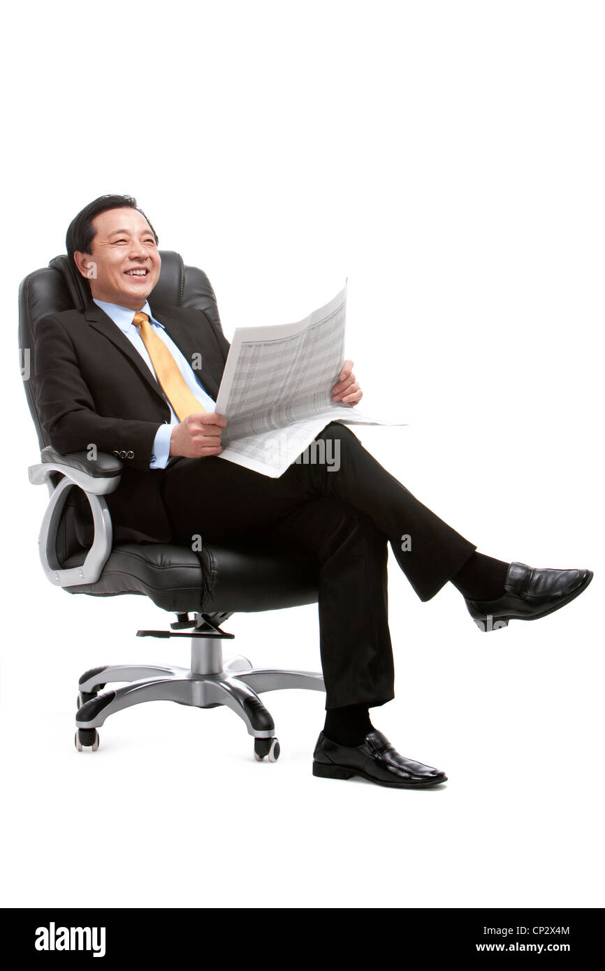 Senior businessman reading newspaper on director's chair Stock Photo ...