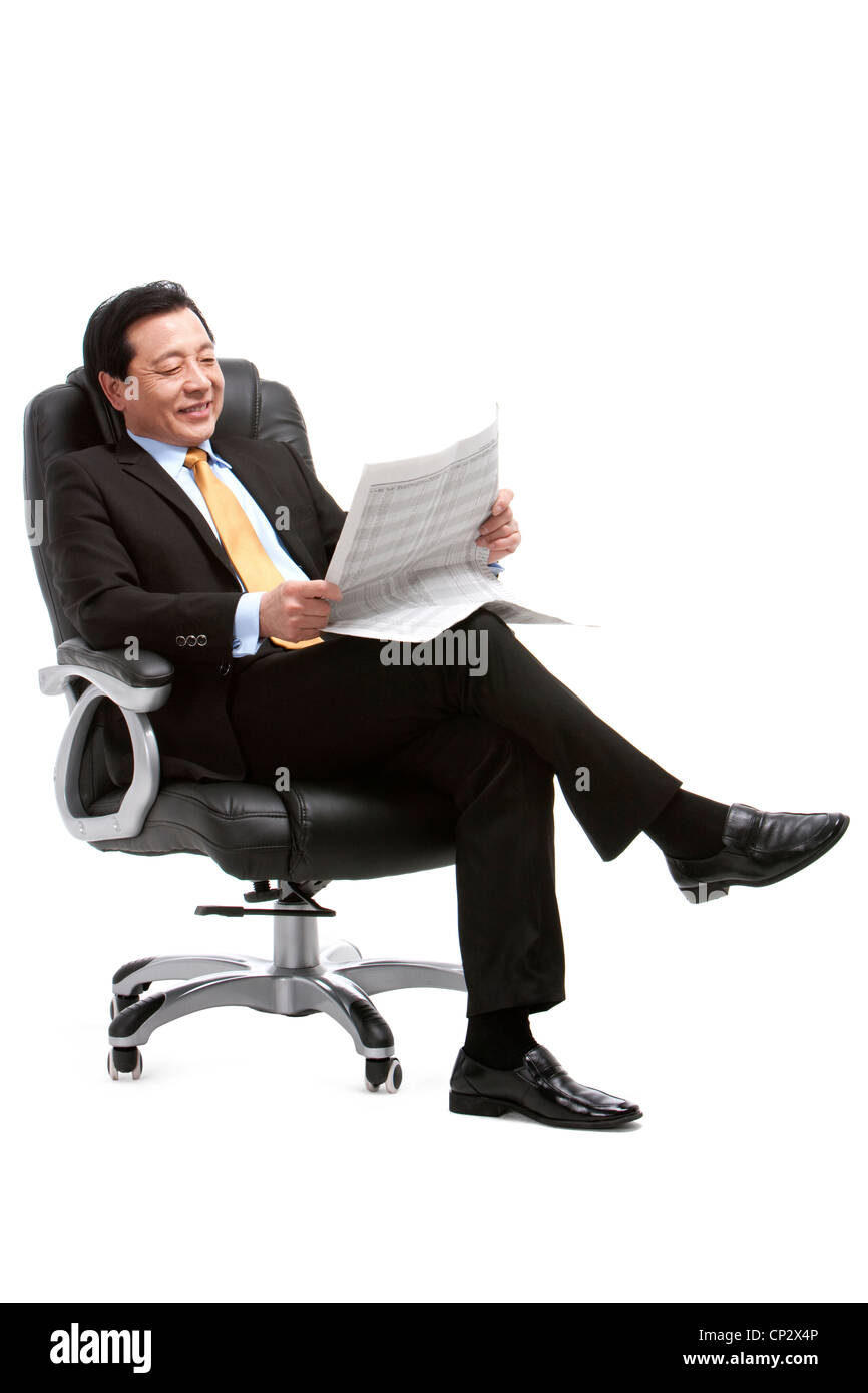 Senior businessman reading newspaper on director's chair Stock Photo ...