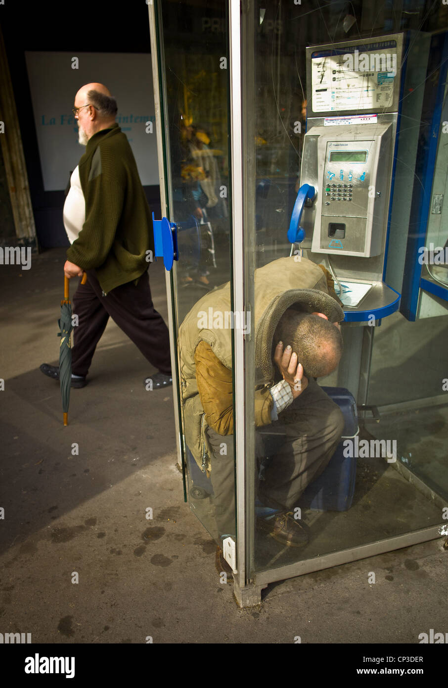 Urban poverty, The old man of the phone booth Stock Photo - Alamy