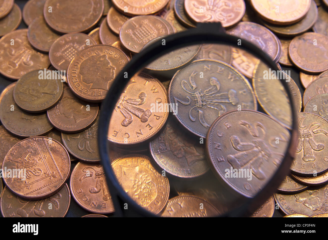 A mound of UK coins being inspected with a magnifying glass Stock Photo ...