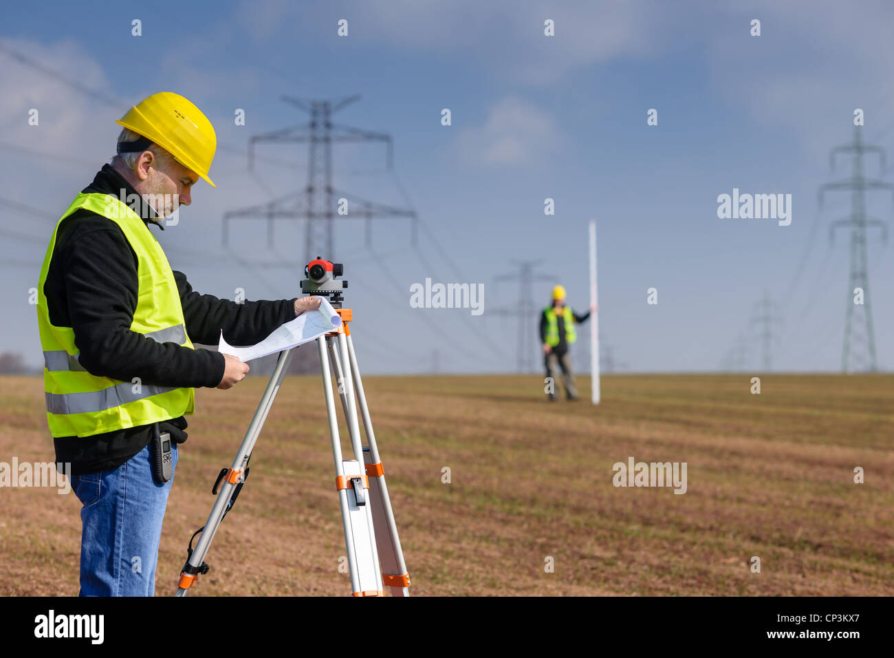 Land surveyors on construction site reading plans wear reflective ...