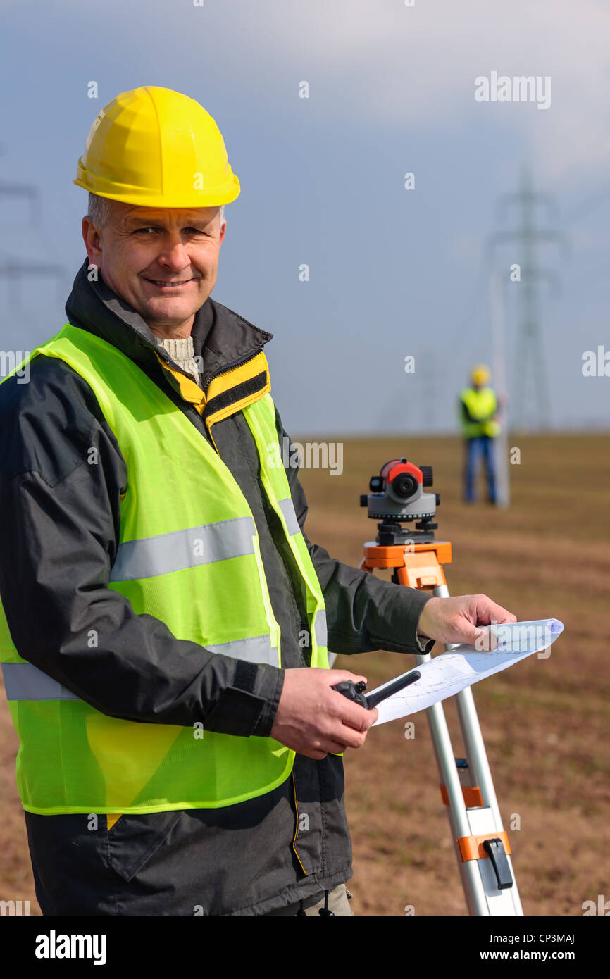 Land surveyors measuring with tacheometer hold construction plans on ...