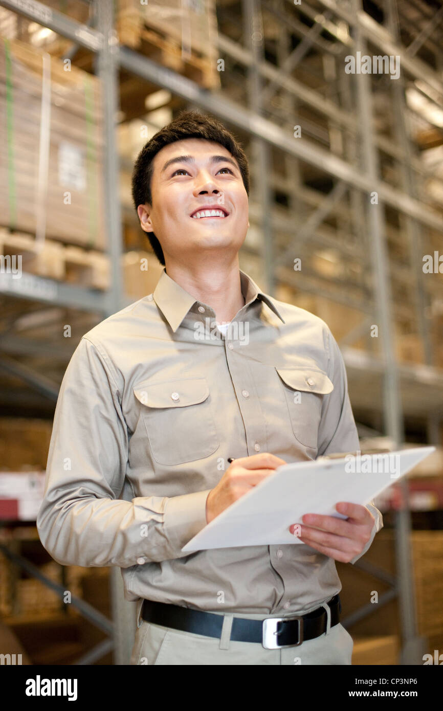 Male Chinese warehouse worker with clipboard Stock Photo - Alamy