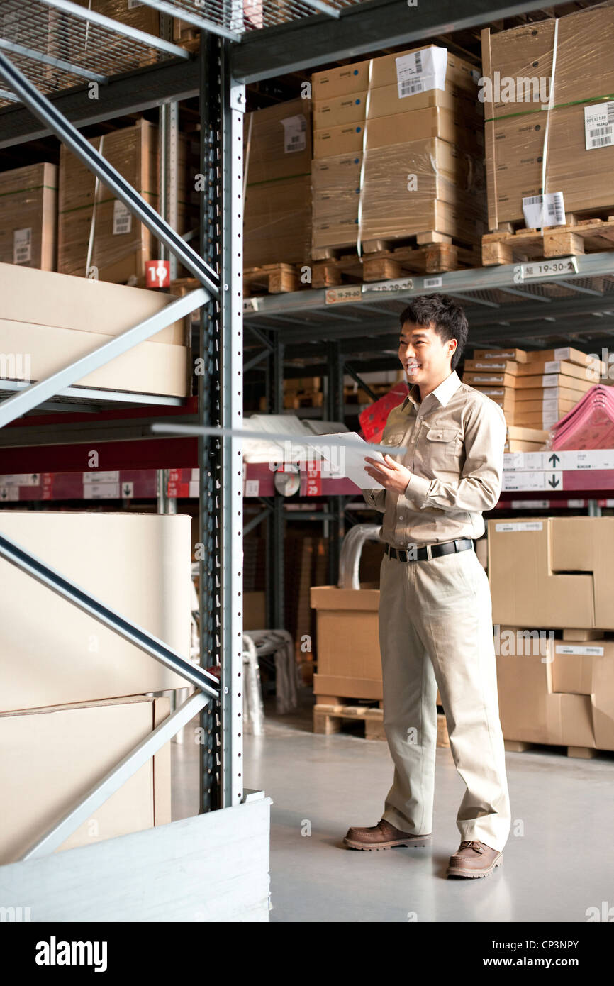 Male Chinese warehouse worker with clipboard Stock Photo - Alamy