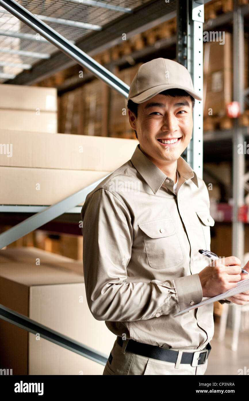 Male Chinese warehouse worker with clipboard Stock Photo - Alamy