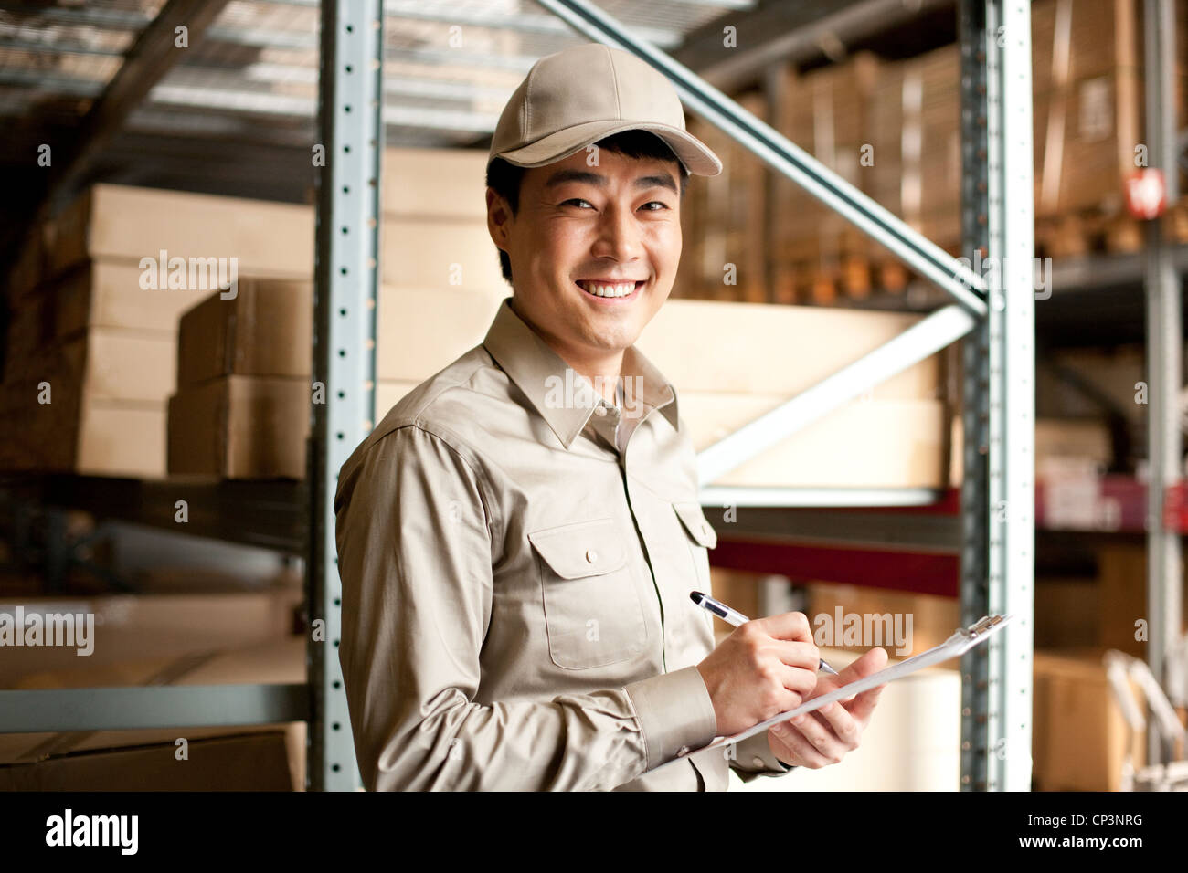 Male Chinese warehouse worker with clipboard Stock Photo - Alamy