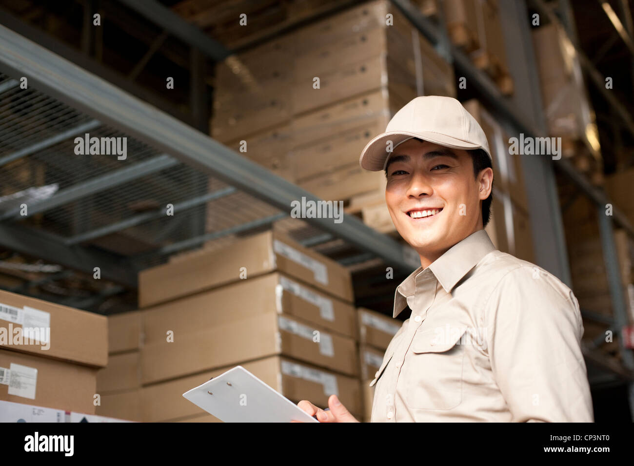 Male Chinese warehouse worker with clipboard Stock Photo - Alamy