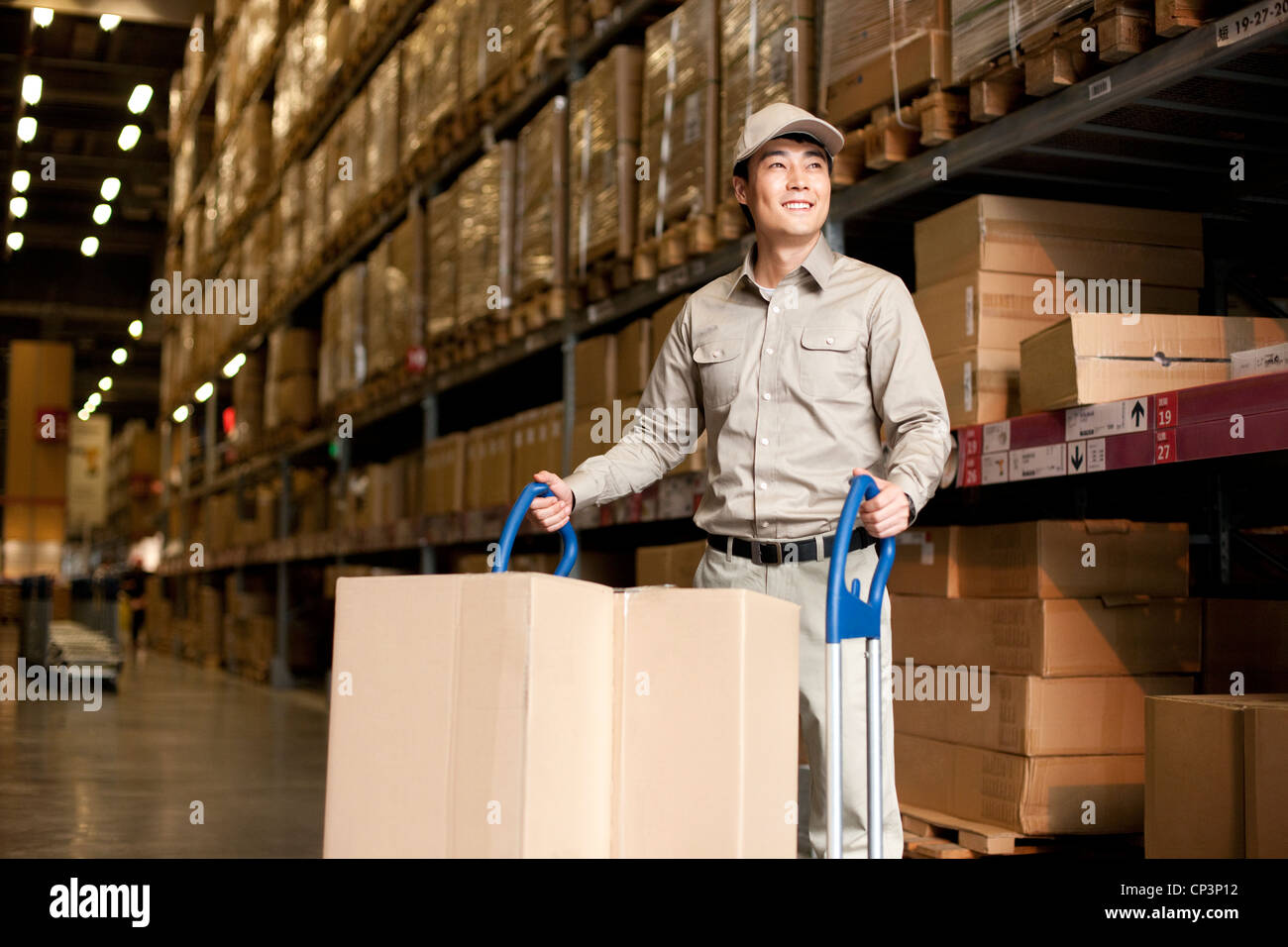 Male Chinese warehouse worker pushing boxes Stock Photo - Alamy