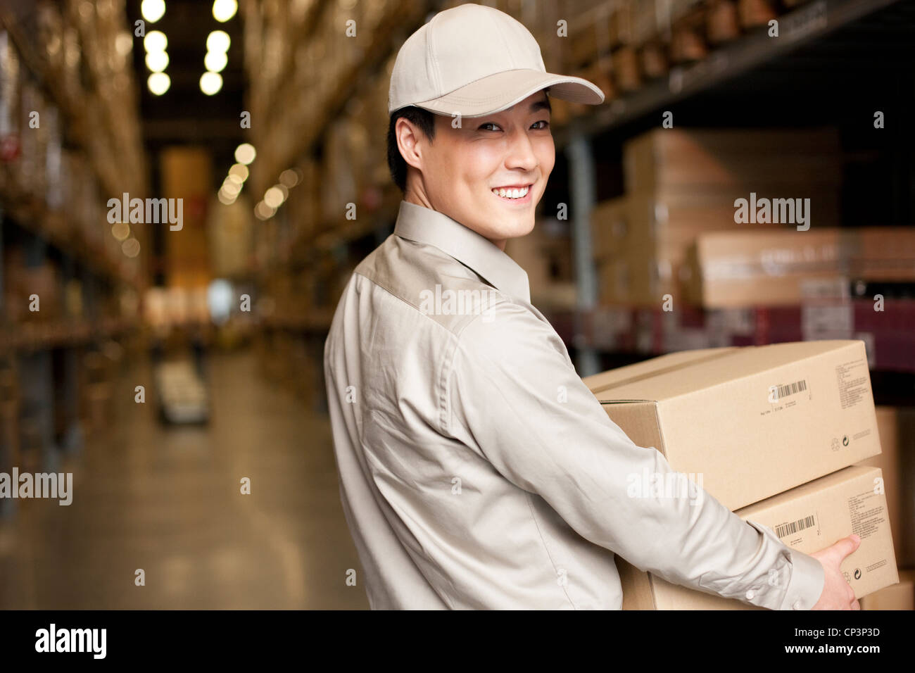Male Chinese warehouse worker carrying boxes Stock Photo - Alamy