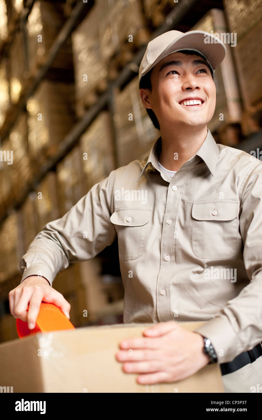 Male Chinese warehouse worker packing a box Stock Photo - Alamy