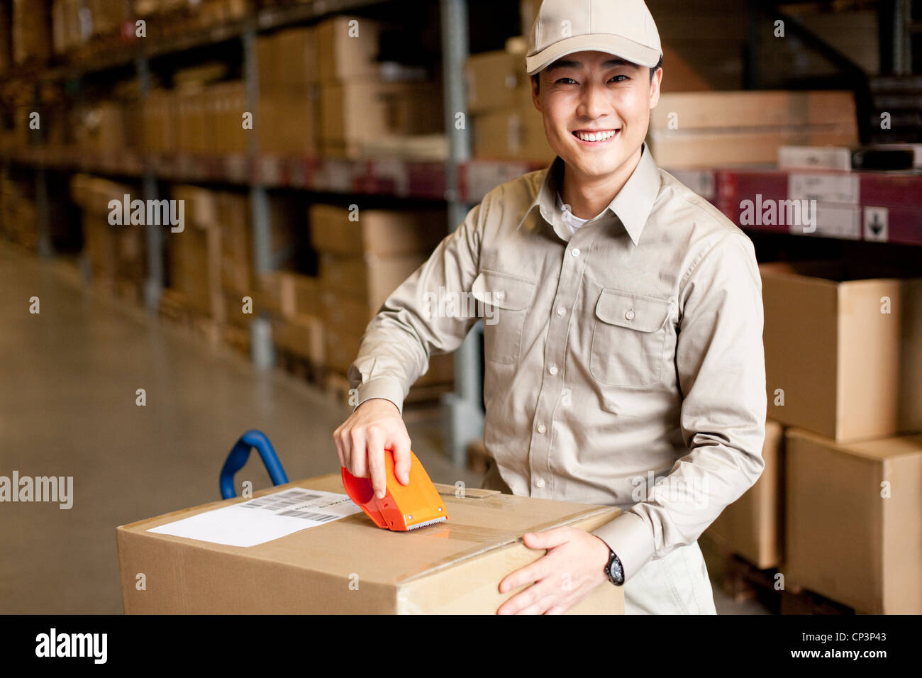 Male Chinese warehouse worker packing a box Stock Photo - Alamy