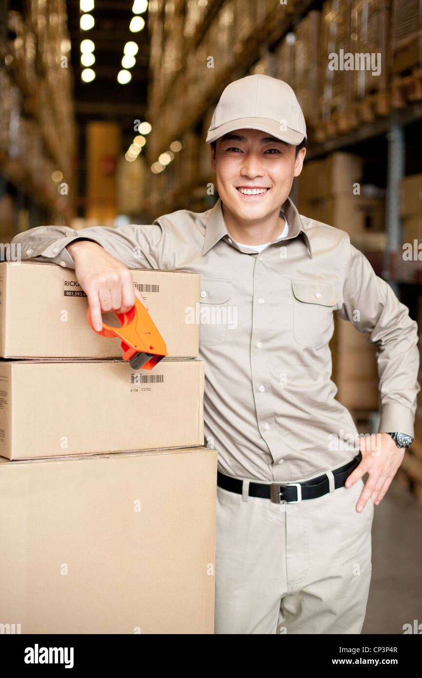 Male Chinese warehouse worker with packed boxes Stock Photo - Alamy