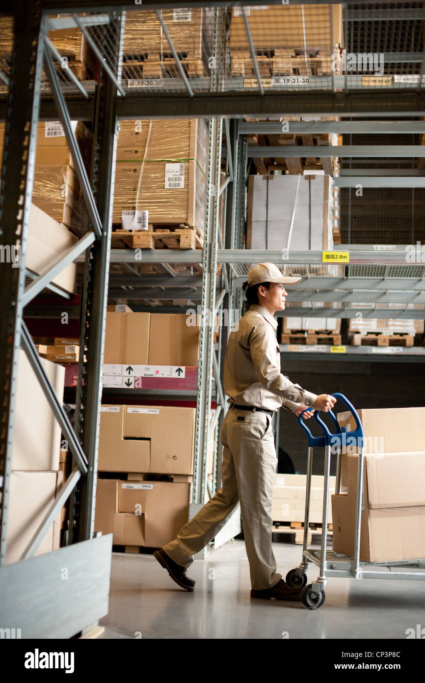 Male Chinese warehouse worker pushing boxes Stock Photo - Alamy
