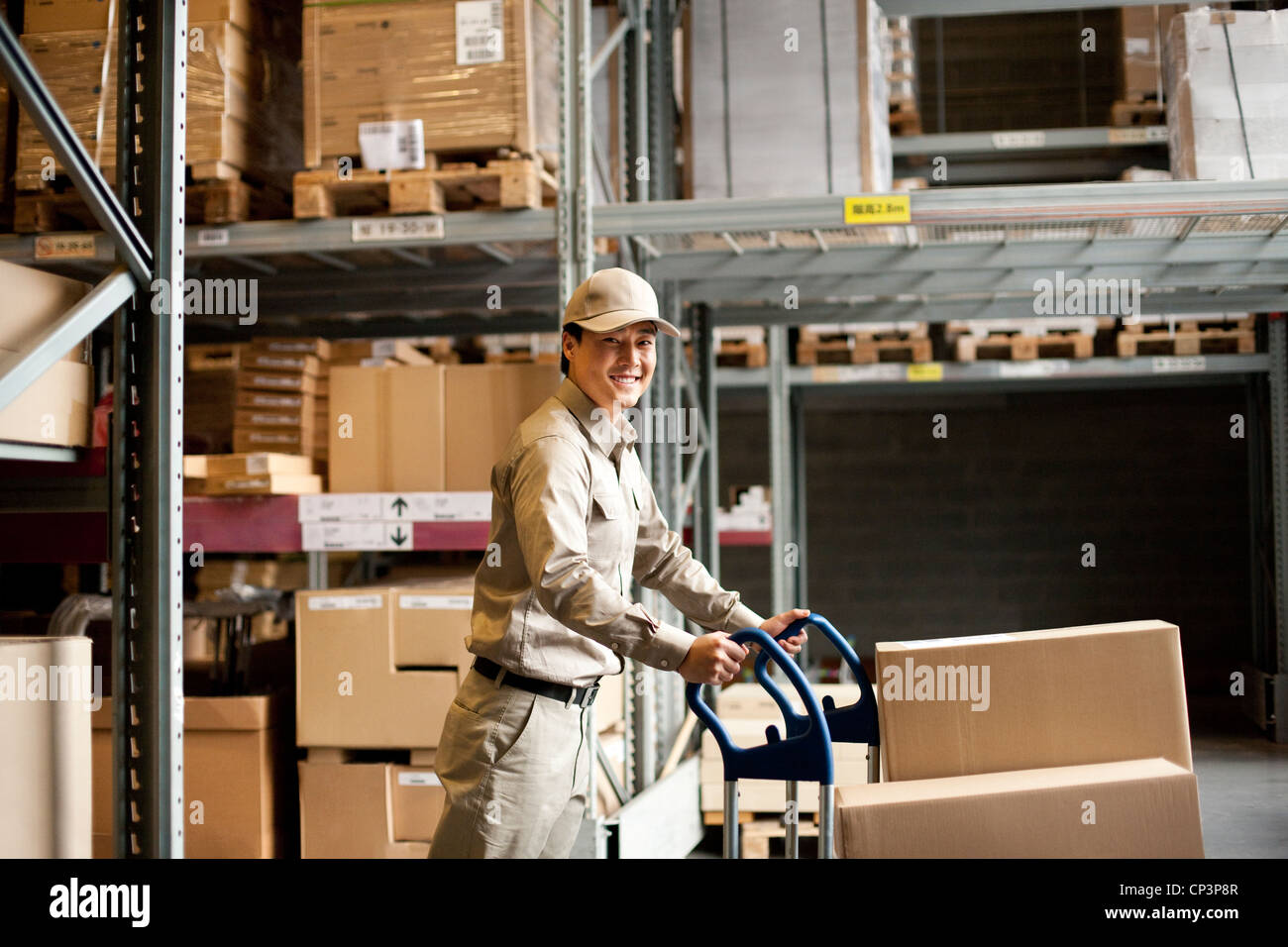 Male Chinese warehouse worker pushing boxes Stock Photo - Alamy
