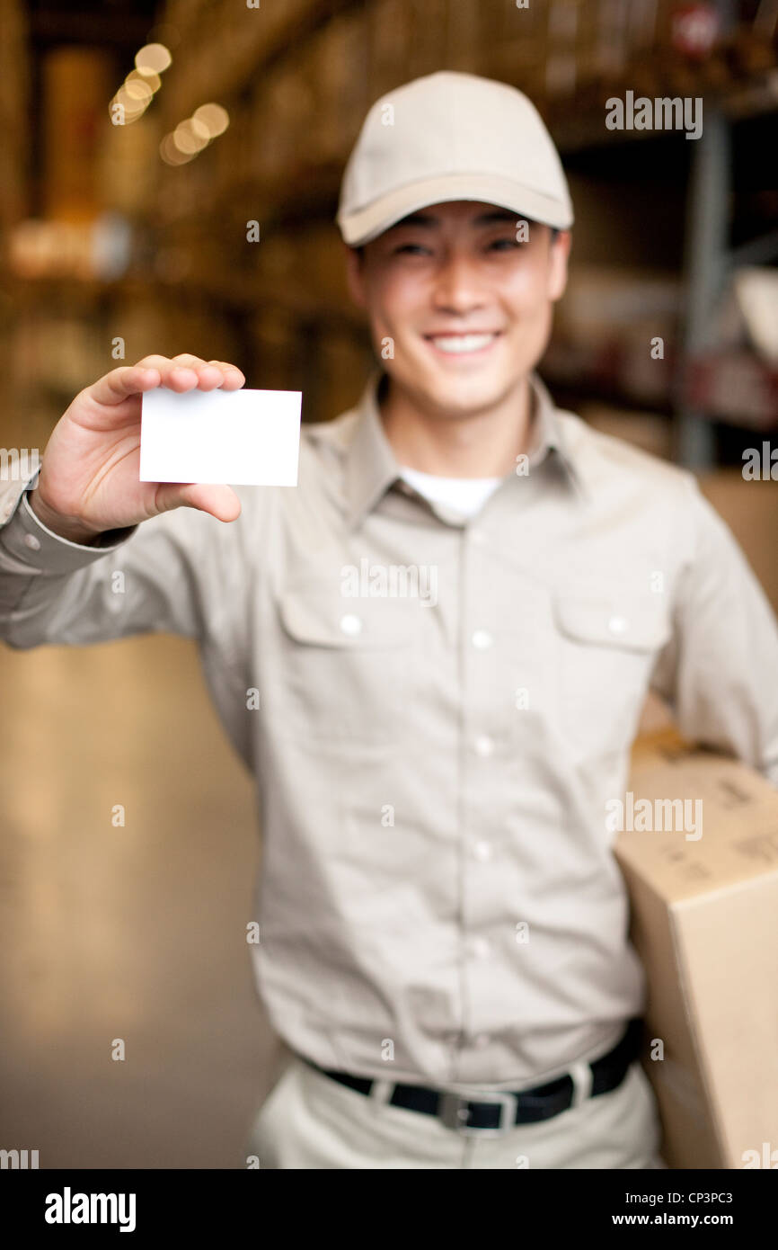 Male Chinese warehouse worker holding up a blank business card Stock ...