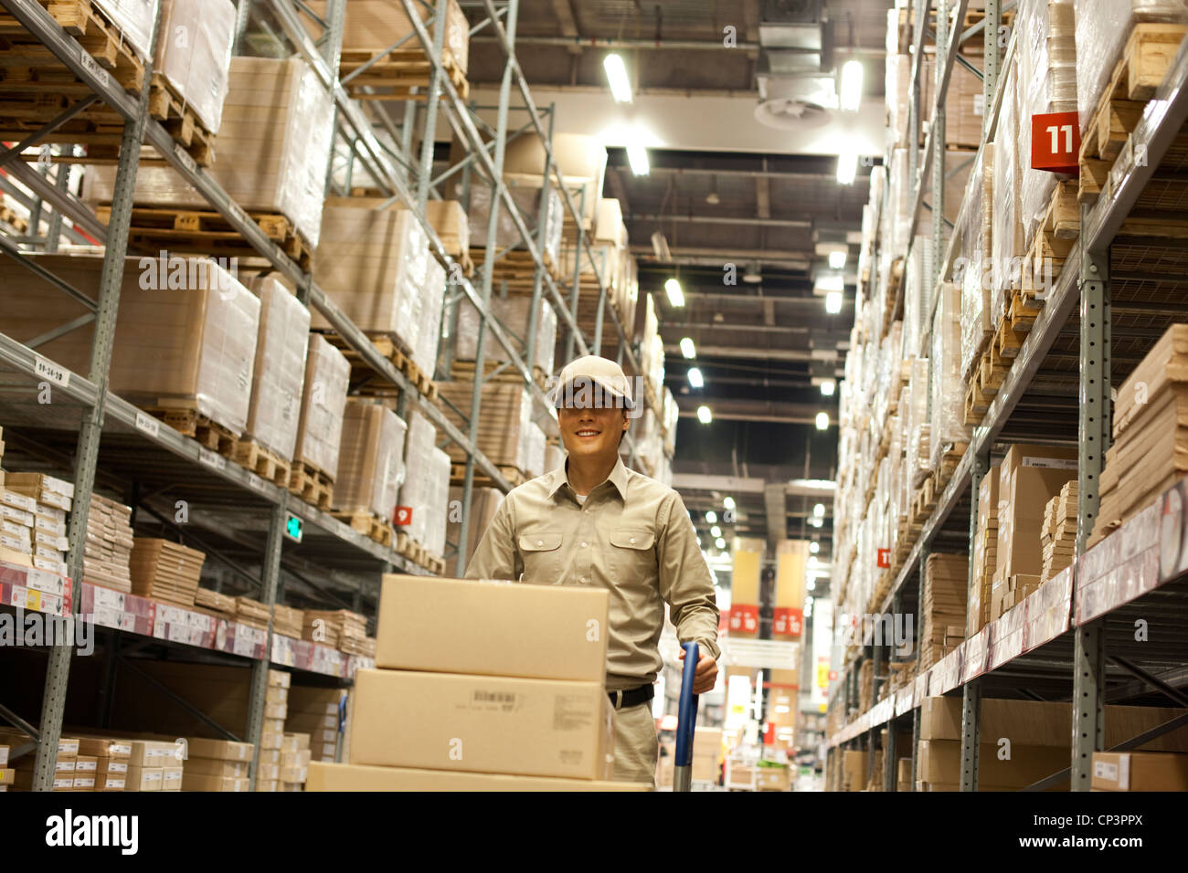 Male Chinese warehouse worker pushing boxes Stock Photo - Alamy