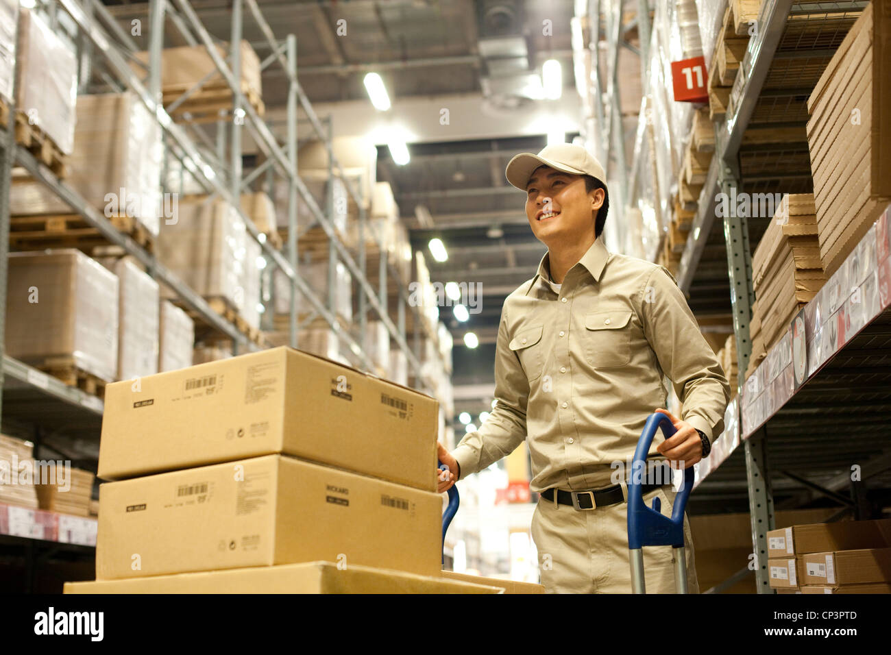 Male Chinese warehouse worker pushing boxes Stock Photo - Alamy