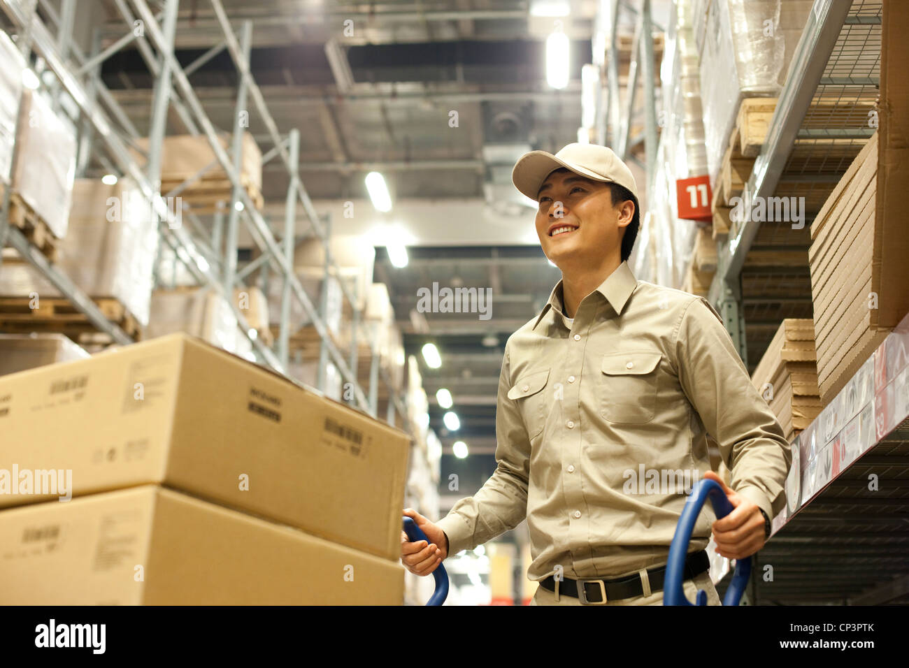 Male Chinese warehouse worker pushing boxes Stock Photo - Alamy