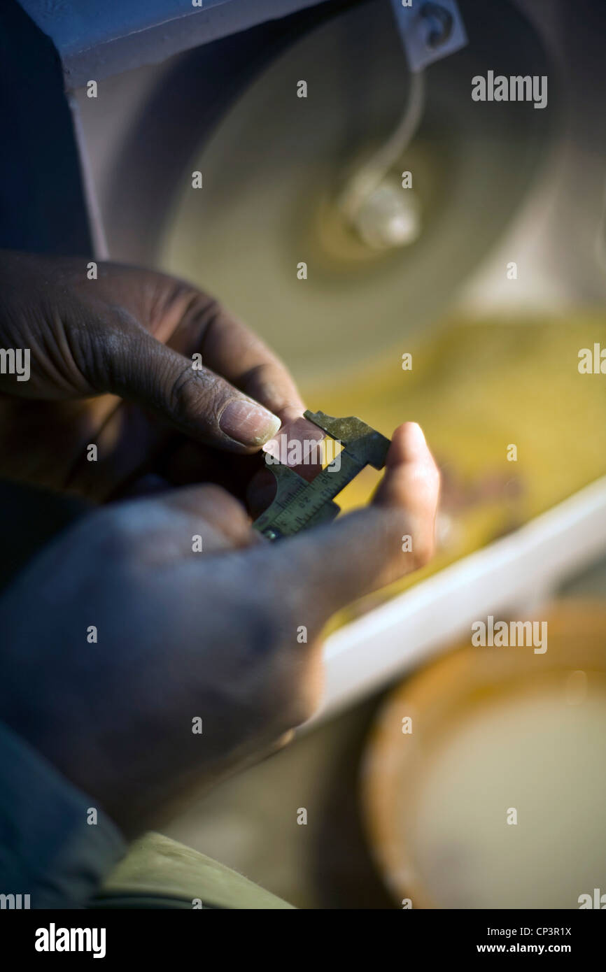 A worker polishing and measuring gem stones in a workshop at the Gem ...