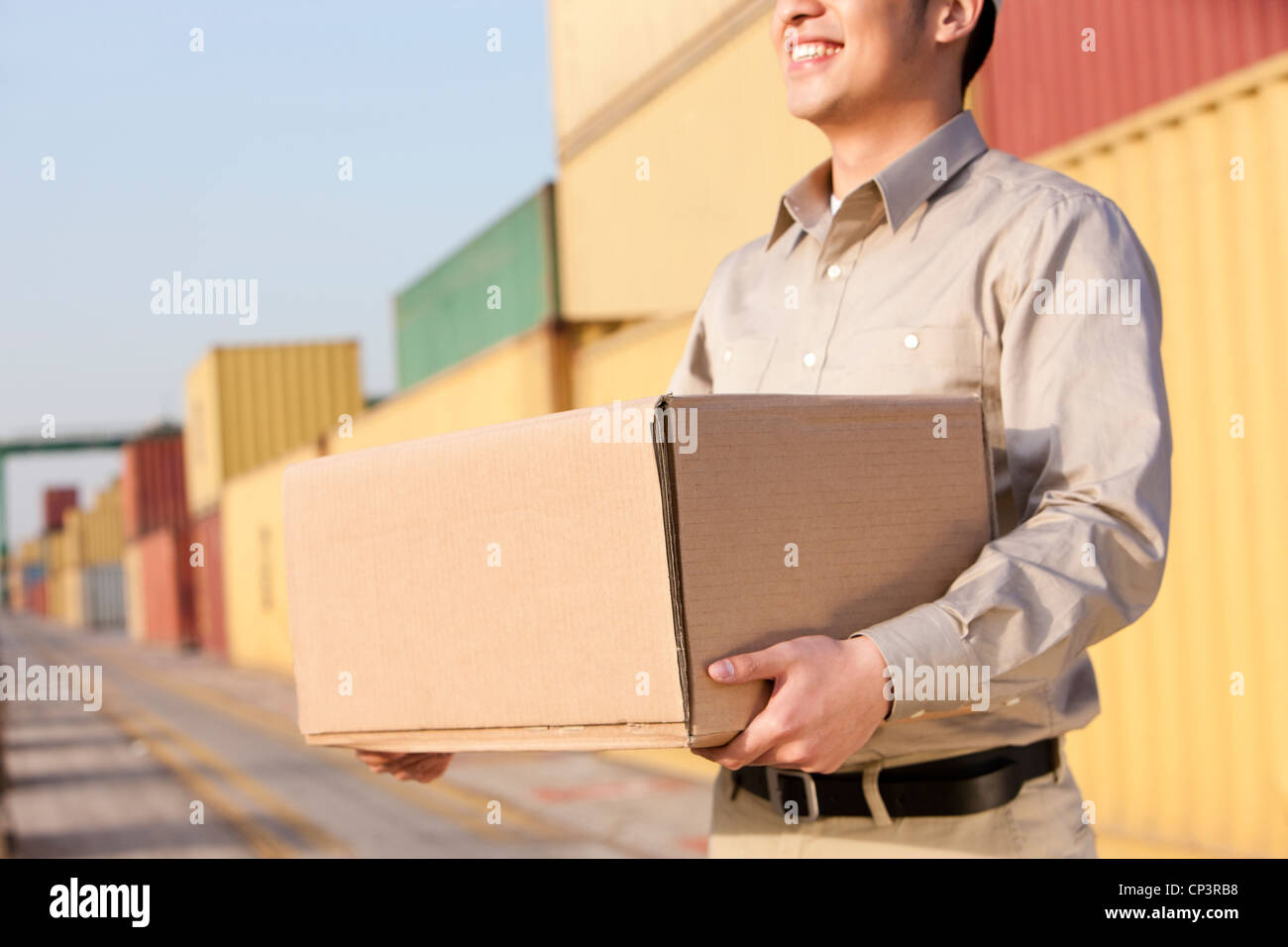 Shipping industry worker carrying a cardboard box Stock Photo - Alamy
