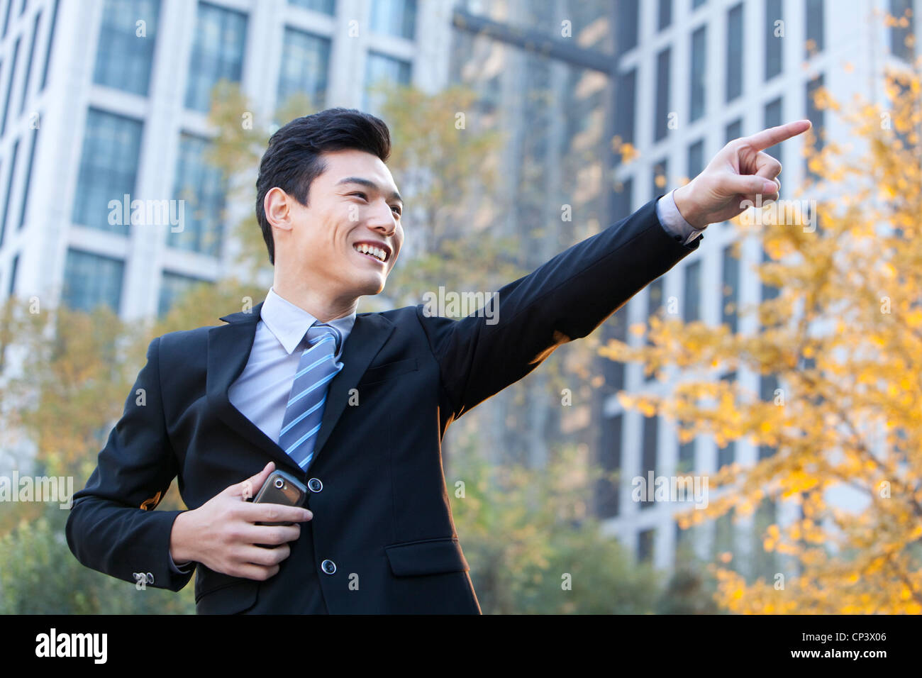 Businessman outside office buildings pointing to something Stock Photo ...