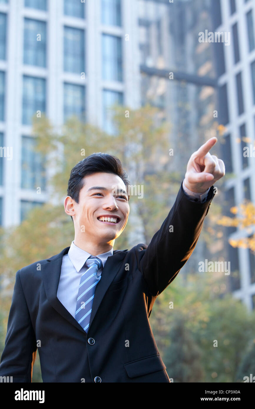 Businessman outside office buildings pointing to something Stock Photo ...