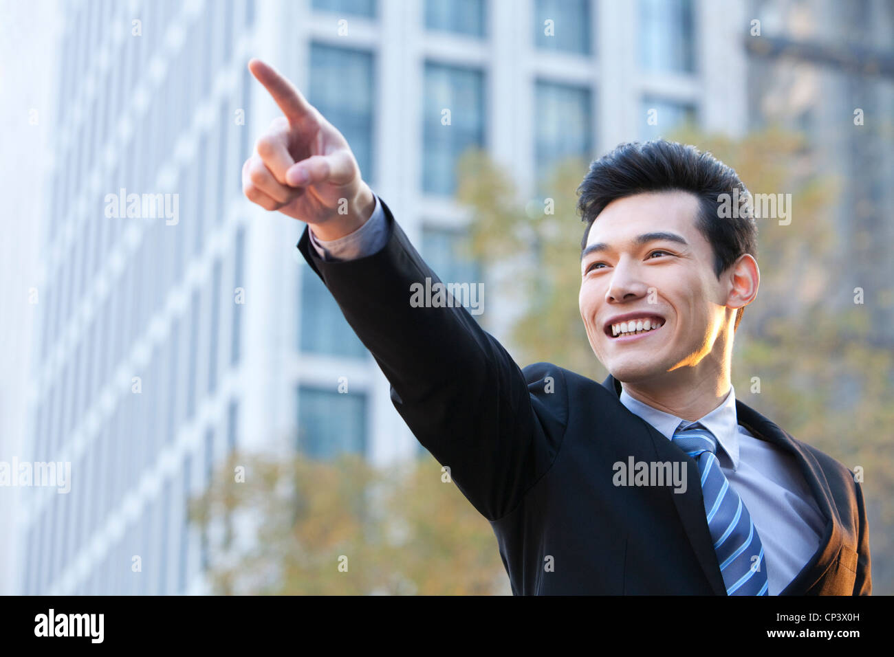 Businessman outside office buildings pointing to something Stock Photo ...