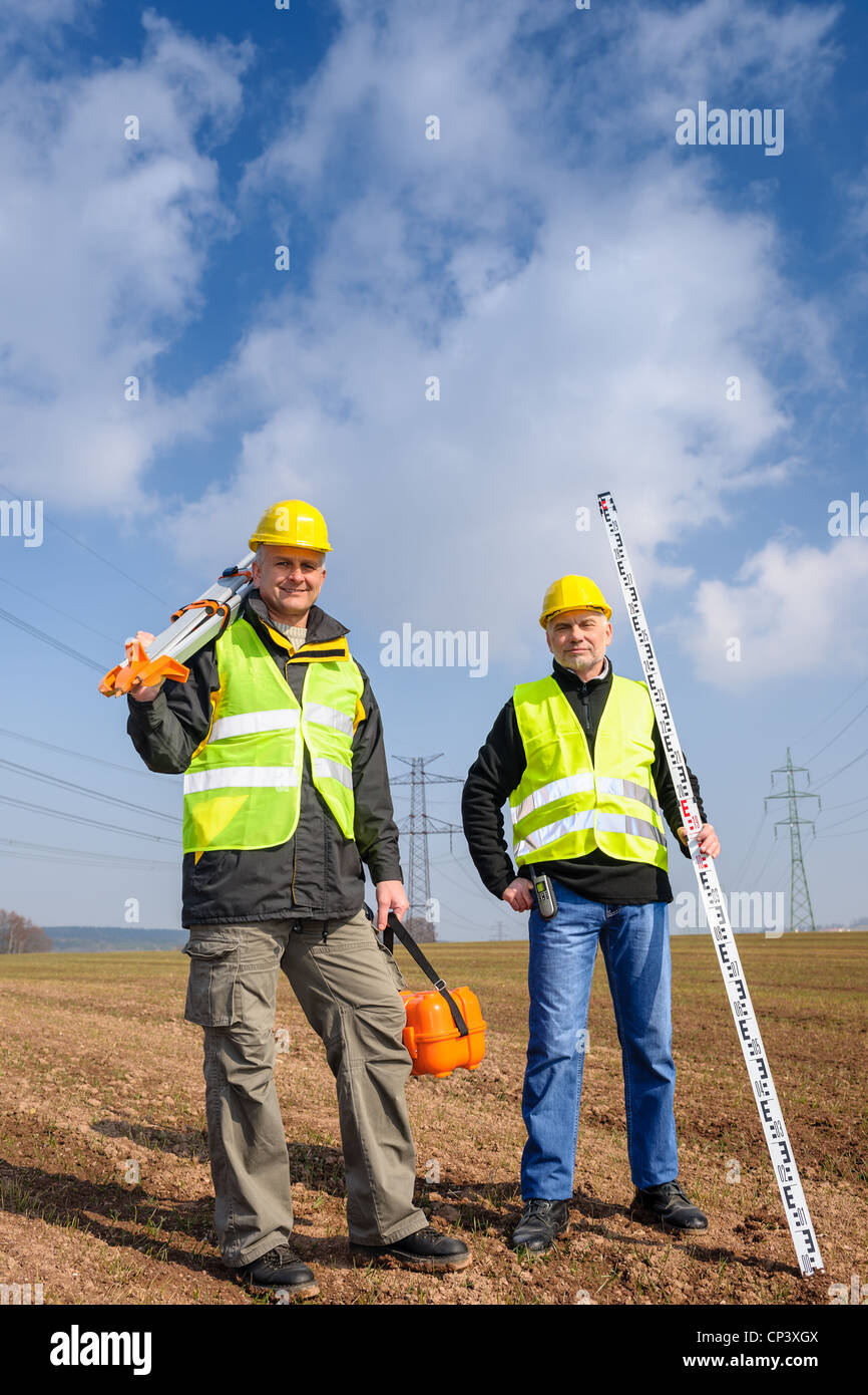 Portrait of two geodesist holding measuring equipment on construction ...